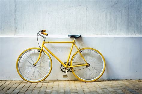 A Vibrant Yellow Bicycle Leans Against A Crisp White Wall Showing A