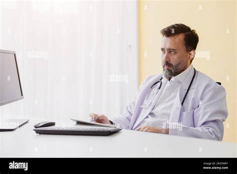 Senior Professional Doctor Male In Hospital Room Working At Table Listening Patient Looking