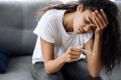 불행한 아픈 아프리카 계 미국인 소녀는 소파에 앉아 건강에 해로운 느낌 그녀는 좌절온도계를 보고 고열이있는 아픈 소녀 그녀는