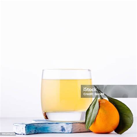 상쾌한 만다린 소다 음료 또는 주스를 흰색 배경에 감귤류와 함께 유리잔에 넣습니다 녹색 나뭇잎과 노란색 흰색 테이블에 오렌지