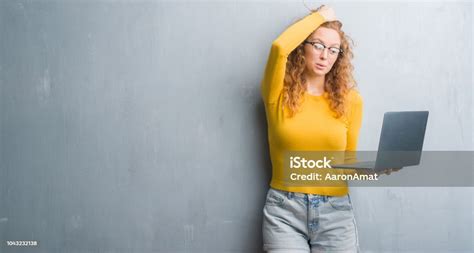 손으로 머리에 강조는 컴퓨터 노트북 들고 회색 그런 지 벽에 젊은 빨강 머리 여자는 수치심과 깜짝 얼굴로 충격 분노와 좌절 두려워 하 고 실수에 대 한 화가 감정에 대한