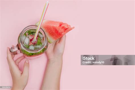 감귤류의 갓 짜낸 수박 레모네이드를 들고 있는 젊은 여성의 손 차가운 칵테일 민트 잎으로 가득 찬 메이슨 항아리가있는 여성 분홍색 배경 복사 공간 닫기 감귤류 과일에 대한