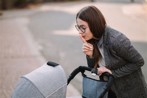 젊은 어머니는 유모차에 그녀의 아기와 함께 걷고 입술에 손가락을 넣어 Shh 를 말하는 엄마 몸짓 침묵 가족에 대한 스톡 사진 및 기타 이미지 Istock