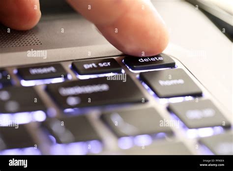 close up of a finger hitting pushing the delete symbol button tab on an illuminated laptop
