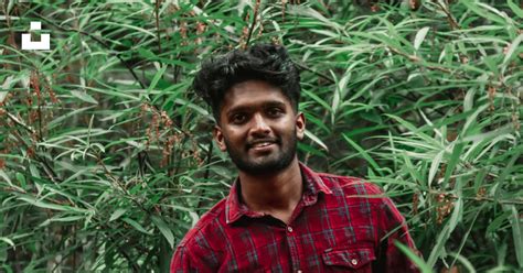 낮 동안 녹색 식물 근처에 서 있는 빨간색과 흰색 격자 무늬 드레스 셔츠를 입은 남자 사진 Unsplash의 무료 미국 이미지