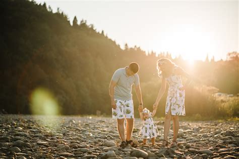 엄마 아빠 딸이 호수 근처에서 돌을 걷고 있습니다 여름 휴가의 개념입니다 어머니 아버지 아기의 날 가족은 자연에 함께 시간을 보내고 가족 모양입니다 태양 빛입니다 아기에
