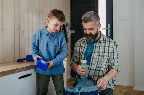 Padre Ayudando A Su Hijo A Prepararse Para El Preescolar Poner La Lonchera Con Aperitivos De