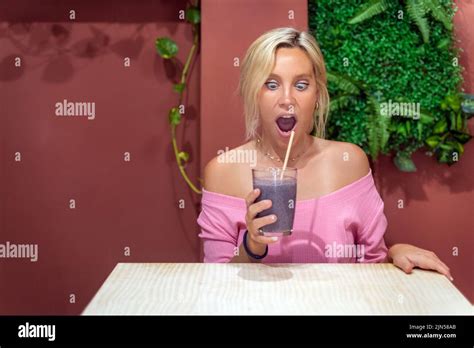 Young Woman Looking Surprised At Her Smoothie While Sitting In A Coffee