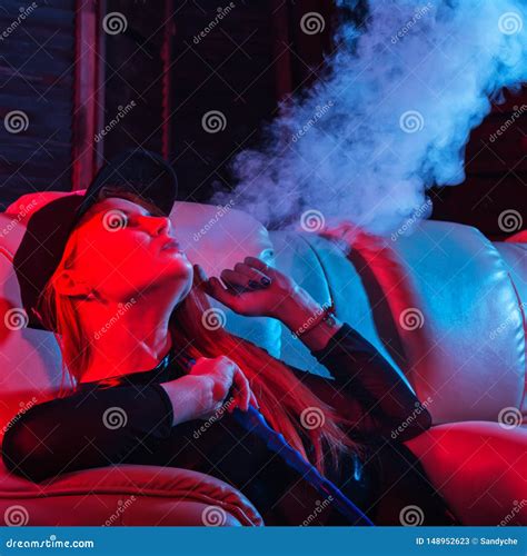Redhead Woman In Black Bodysuit Sitting On A Sofa And Smokes Hookah Girl Blows Out Big Smoke