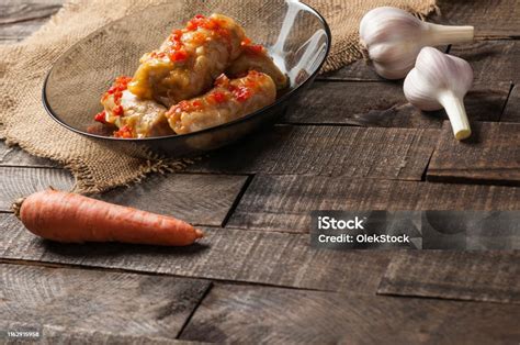 삶은 양배추 롤의 한 부분과 쌀과 고기로 채워진 토마토 소스가 마늘 근처의 검은 유리 판에 당근은 가라앉고 소박한 나무 테이블에 갈색에 대한 스톡 사진 및 기타 이미지