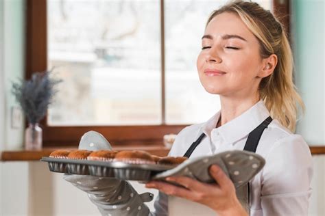 Free Photo Close Up Of A Smiling Young Woman Smelling The Fresh Baked Muffins