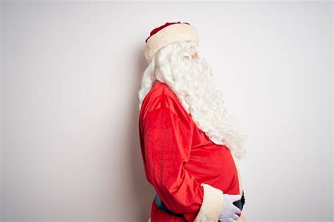 산타 의상을 입은 중년 잘생긴 남자는 옆으로 찾고 고립 된 흰색 배경 위에 서서 자연스러운 얼굴과 자신감있는 미소로 프로필