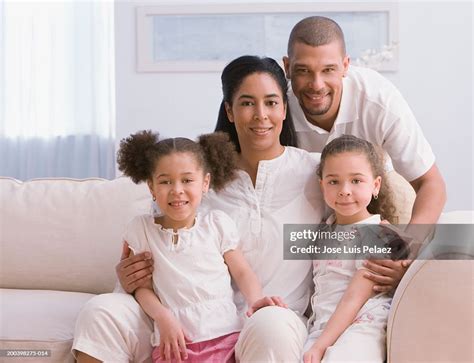 Mom And Dad With Two Daughters On Couch Smiling Portrait High Res Stock