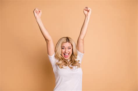 그녀의 초상화 그녀 보기 사랑스러운 매력적인 쾌활한 쾌활한 쾌활한 낙관적 물결 모양의 머리 아가씨 는 베이지 색 파스텔 배경을 통해 고립 된 좋은 승리를 올리면 손을 올리고