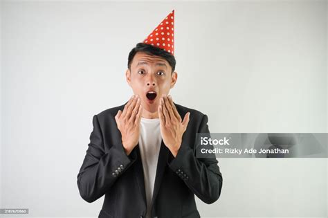 빨간 파티 모자 흰 셔츠와 검은 색 양복을 입은 놀란 젊은 아시아 남자는 흰색 배경에 고립 된 상 또는 좋은 소식을 얻습니다 크리스마스 휴일 새해 파티를 위한 컨셉 12월