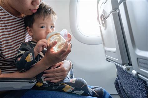 물을 마시는 아기 소년과 함께 비행기를 타는 어머니 비행기에서 어머니 무릎에 앉아 비행하는 비행기로 여행하는 아기 젖병에 대한 스톡 사진 및 기타 이미지 Istock