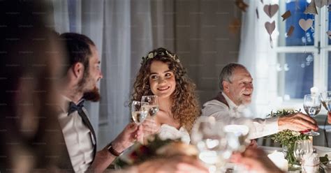 신랑 신부와 다른 하객들이 결혼식 테이블에 앉아 안경을 부딪치고 있다 사진 Unsplash의 결혼식 이미지