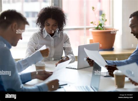 Colleagues Analyzing Statistics While Brainstorming In Office Together