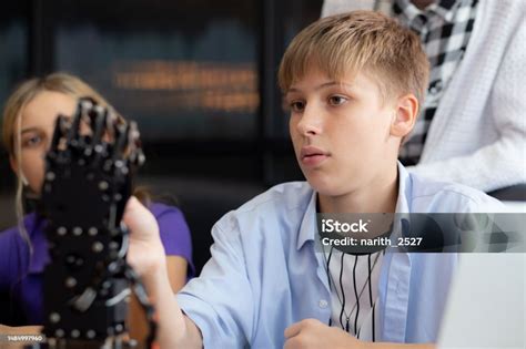 백인 두 명의 십대 학생들이 학교에서 함께 교실에서 로봇 팔을 배우고 소년과 소녀는 교사 교육 및 개발 개념과 함께 인지와 함께 로봇 Ai를 연구합니다 3 명에 대한 스톡