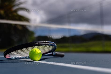 Close Up Of Tennis Ball And Tennis Racket Lying On Tennis Court On Sunny Day Copy Spaceの写真素材
