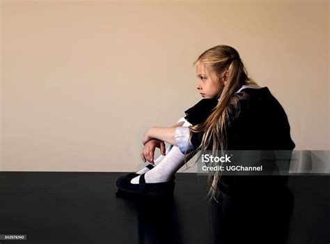 Beautiful Blond Girl Sitting On The Floor Hugging Knees Hands Stock
