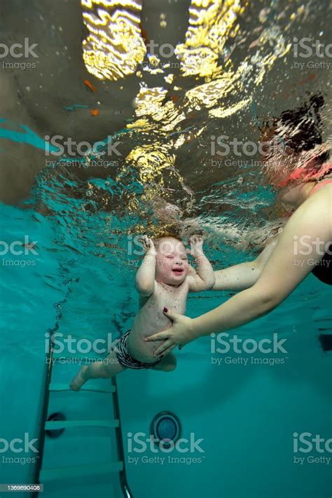 Un Bebé Feliz Con Síndrome De Down Nada Hacia Las Manos De Su Madre