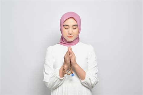 흰색 배경 위에 격리된 타스비와 함께 신에게 기도하는 젊은 아시아 무슬림 여성 프리미엄 사진