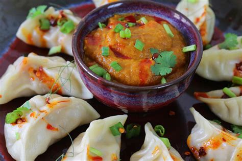 찐 모모 닭고기와 혼합 야채로 채워진 흰 밀가루와 물 반죽 칠리 오일이 뿌려진 오렌지 매운 디핑 소스의 라메킨을 둘러싼 접시에 올려진 모습 높은 전망 0명에 대한 스톡 사진