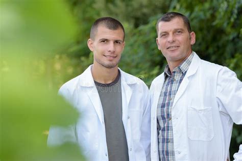 Engineers Examining Robotic Gripper Arm During Industrial Automation Training Session Stock