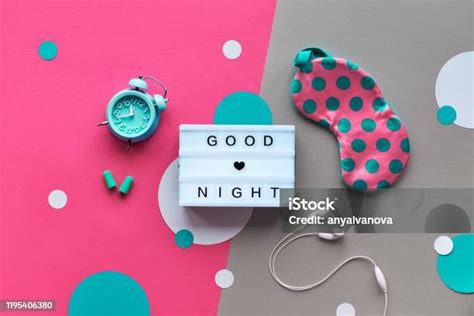 건강 한 야 면 창의적 평평 수면 마스크 알람 시계 이어폰 귀마개 차 및 알약 분홍색과 공예 종이 배경을 밝은 화환으로 분할합니다 라이트 박스 텍스트 안녕히 주무세요 개념에