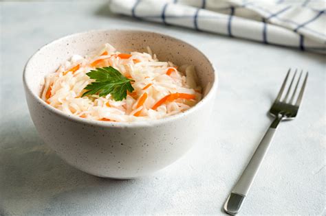 흰색 세라믹 그릇에 수제 소금에 절인 양배추 근처에는 금속 포크와 수건이 있습니다 요리는 파슬리 잎으로 장식되어 있습니다 맛있는