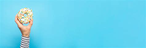 여성의 손은 파란색 배경에 도넛을 들고 있다 컨셉 제과 점 패스트리 커피 숍 배너 플랫 레이 상단 보기 끈적거리는에 대한 스톡 사진 및 기타 이미지 Istock