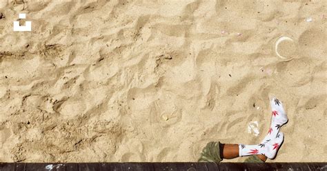 검은 바지와 흰색 빨간색과 파란색 꽃 운동화를 신은 사람이 갈색 모래 위에 서 있습니다 사진 Unsplash의 무료 모래 이미지