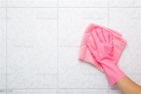 분홍색 고무 보호 장갑에 여자 손 은 마른 걸레와 밝은 회색 세라믹 타일 벽을 닦아 근접 촬영 봄 일반 또는 정기적 인 청소