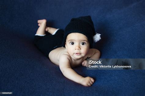 짙은 파란색 모자를 쓴 귀여운 신생아 어두운 파란색 배경에 행복한 아기 신생아의 클로즈업 초상화 아기 상품 포장 템플릿 보육 의료 및 건강 한 개념 크리스마스 새해 6 11