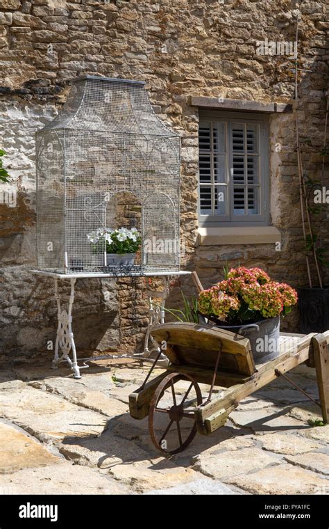 Wooden Wheelbarrow With Hydrangea And Wisteria In Metal Pot Outside