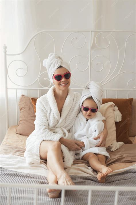 Fashion Mom And Her Daughter Laying On Bed After Spa In Hotel Room In