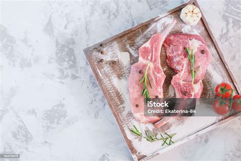 생 돼지고기의 조각 회색 돌 배경에 공간을 복사 합니다 토마토 마늘 로즈마리가 있는 고기 스테이크 2 개 텍스트에 대 한 장소