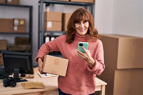 사무실에서 스마트폰 소지 패키지를 사용하는 중년 여성 전자상거래 비즈니스 근로자 Brand Name Smart Phone에 대한 스톡 사진 및 기타 이미지 Brand