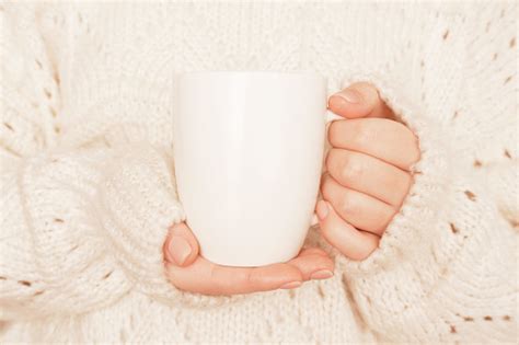 모의 흰 컵을 들고 여자 손 머그잔 클로즈업 흰색 니트 스웨터를 착용하는 여성 빈 템플릿 로고 텍스트 디자인 홍보 문자 메시지