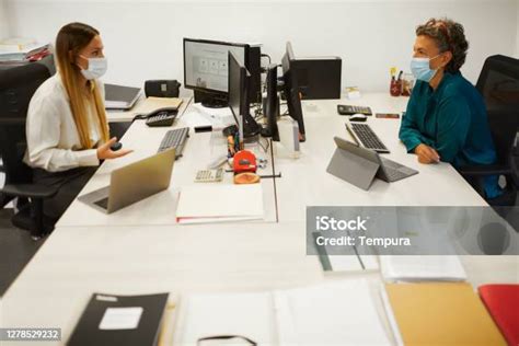 두 명의 사무직 근로자가 말하고 보호얼굴 마스크를 쓰고 있다 사무실에 대한 스톡 사진 및 기타 이미지 사무실 소기업 팬데믹 질병 Istock
