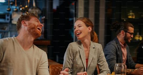 매력적인 미소 짓는 백인 금발이 식당에 앉아 저녁을 먹고 친구와 이야기를 나눕니다 배경에는 친구가 있습니다 사진 Unsplash의 세르비아 이미지