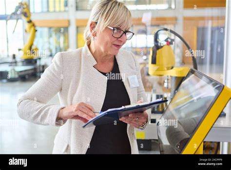 Female Engineer Programming An Industrial Robot With Gripper Arm In A