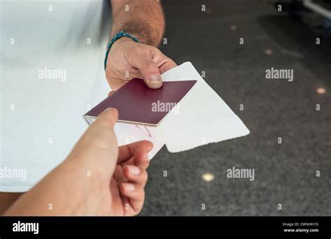 Closeup Hand Of Traveler Showing Passport And Boarding Pass At Terminal Security Check Stock