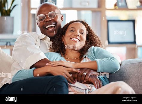 Couple Hug And Laughing On Sofa Portrait In Home Living Room Bonding