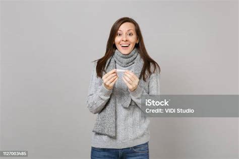 스튜디오에서 회색 벽 배경에 고립 된 온도계를 들고 회색 스웨터 스카프에 즐거운 흥분된 젊은 여자 건강 한 라이프 스타일 아픈