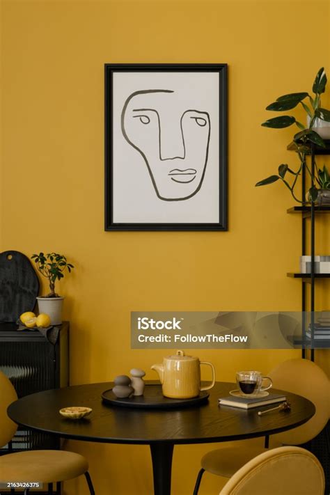 모형 포스터 프레임 원형 테이블 노란색 의자 드라이 플라워가 담긴 유리 꽃병 램프 및 개인 액세서리가있는 따뜻한 식당 인테리어의 세련된 구성 가정 장식 템플렛 0명에 대한