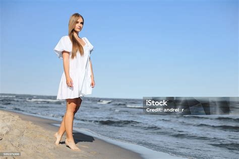 행복한 미소를 짓는 아름다운 여자가 하얀 여름 드레스를 입고 바다 해변을 걷고 있다 18 19세에 대한 스톡 사진 및 기타 이미지 18 19세 건강한 생활방식 걷기