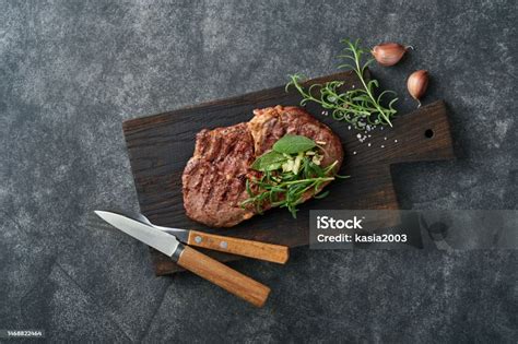 스테이크 얇게 썬 구운 고기 스테이크 뉴욕 또는 Ribeye는 오래된 나무 배경에 검은 대리석 보드에 향신료 로즈마리와 후추를 곁들입니다 평면도 모의 티본 스테이크에 대한