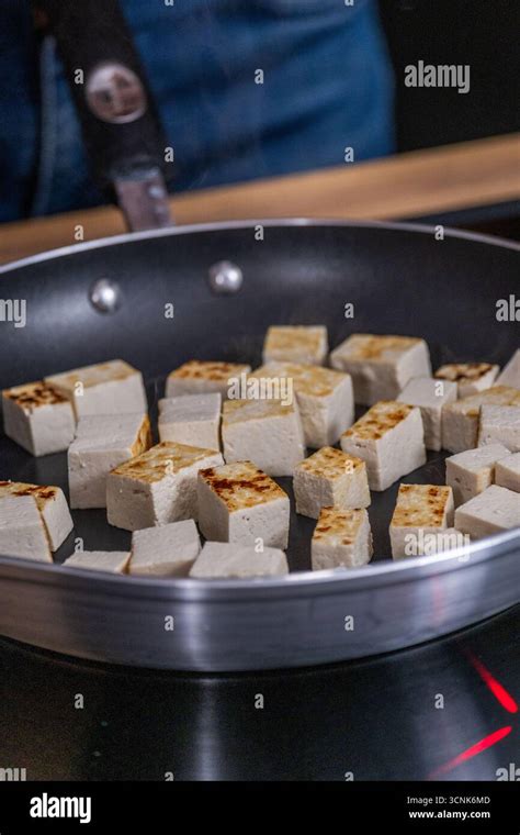 Cubes Of Tofu Are Being Cooked In A Frying Pan On A Stovetop
